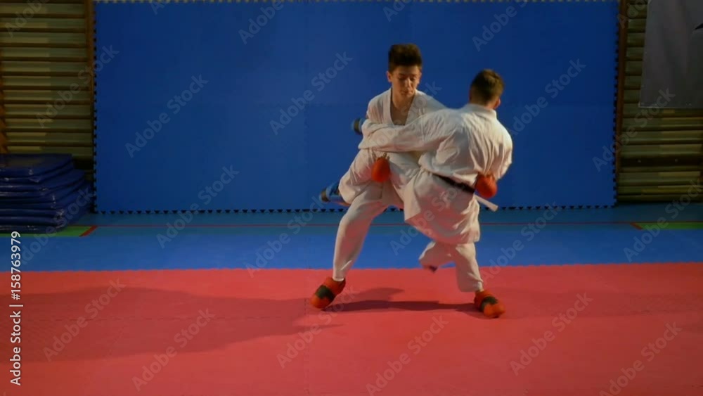 Two boys fighting in a combat and one puts down the other with martial ...