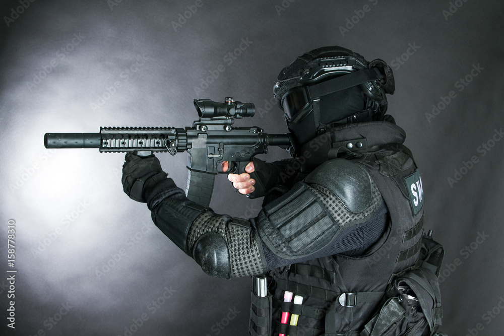 Member of the SWAT squad with an assault rifle in a black uniform on ...