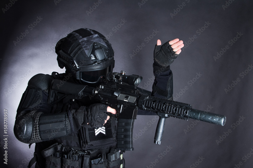 Member of the SWAT squad with an assault rifle in a black uniform on ...