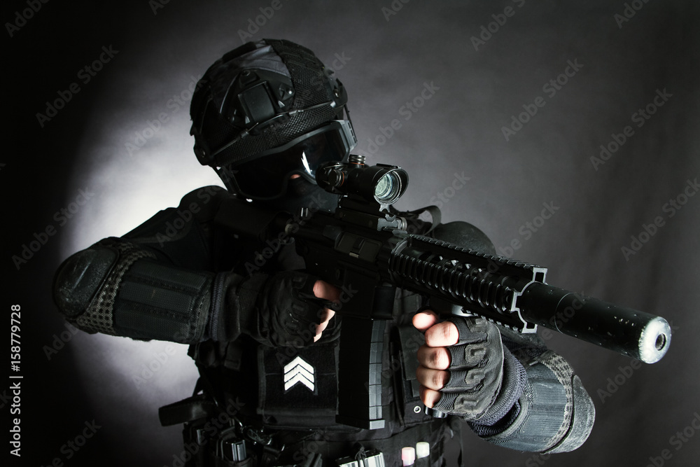 Member of the SWAT squad with an assault rifle in a black uniform on ...