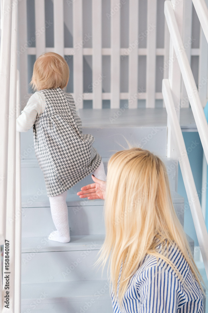 Young beautiful happy mother help her daughter doing her first step ...