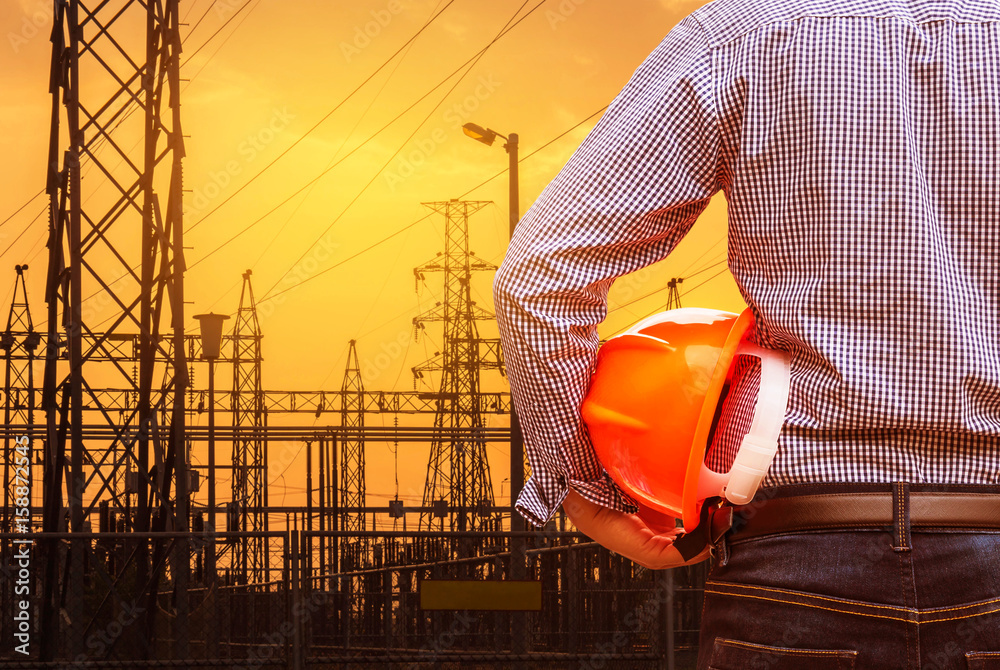 engineer holding safety helmet with high voltage electric pillars ...