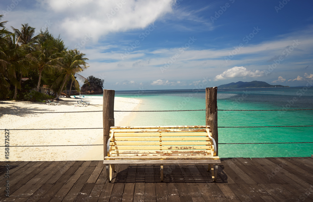 Wood deck with bench and ocean in beautiful tropical beach background ...