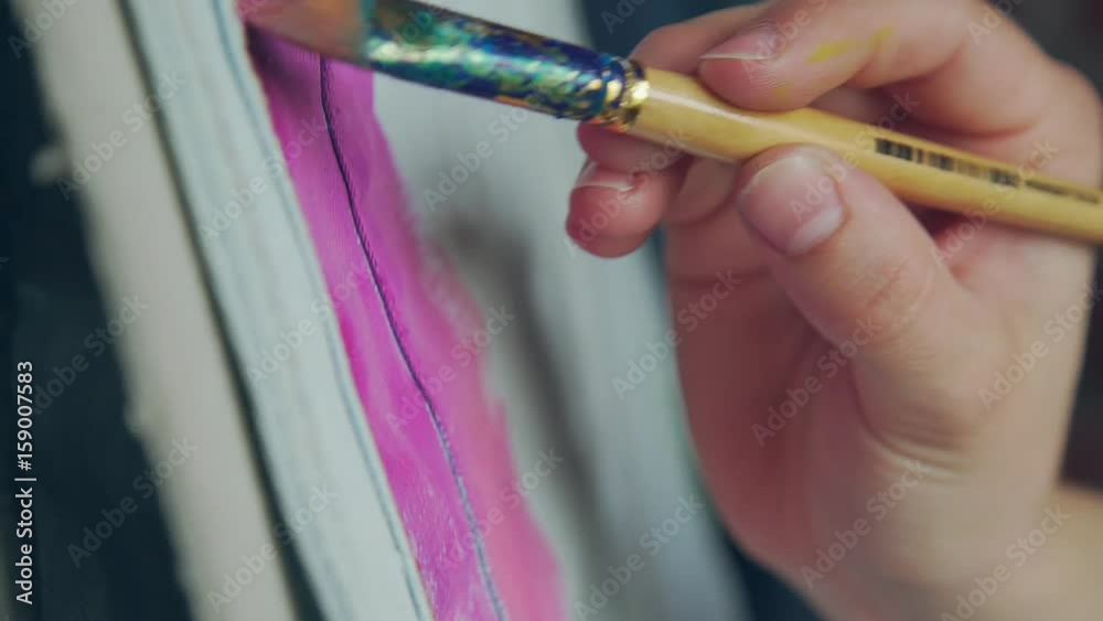 Brush for drawing with pink paint, drawing on denim. Close-up: process ...