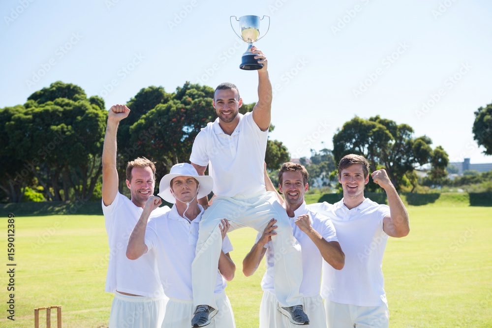 Happy cricket team with trophy standing on field Stock Photo | Adobe Stock
