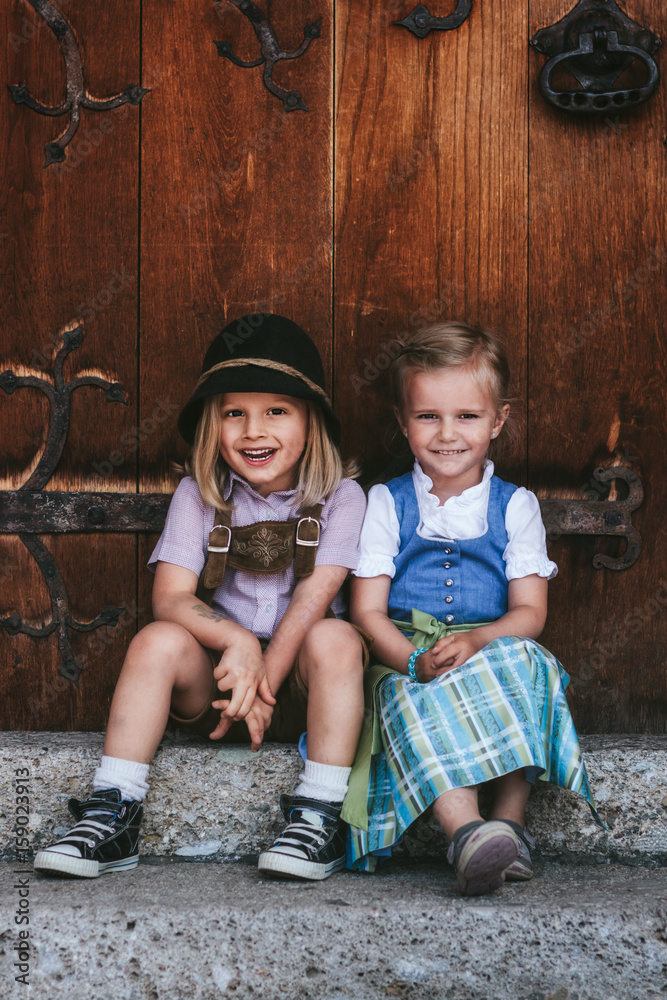 cute smiling children couple in typical austrian outfit sitting in ...