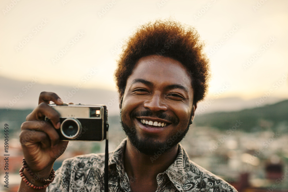 Young black man holding an old camera at sunset Stock Photo | Adobe Stock