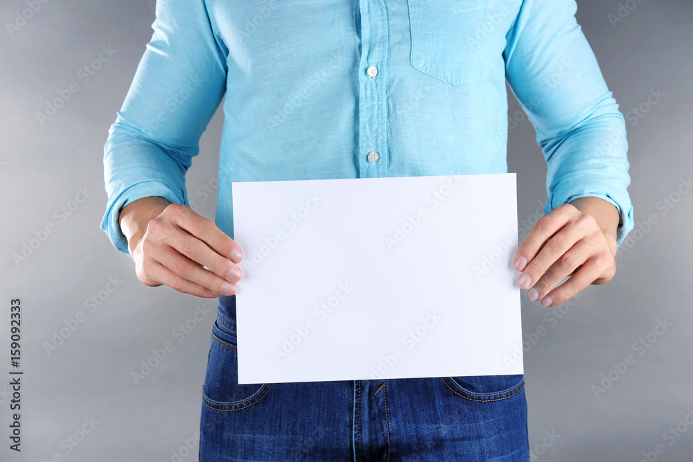 Man holding sheet of paper with space for text on grey background Stock ...