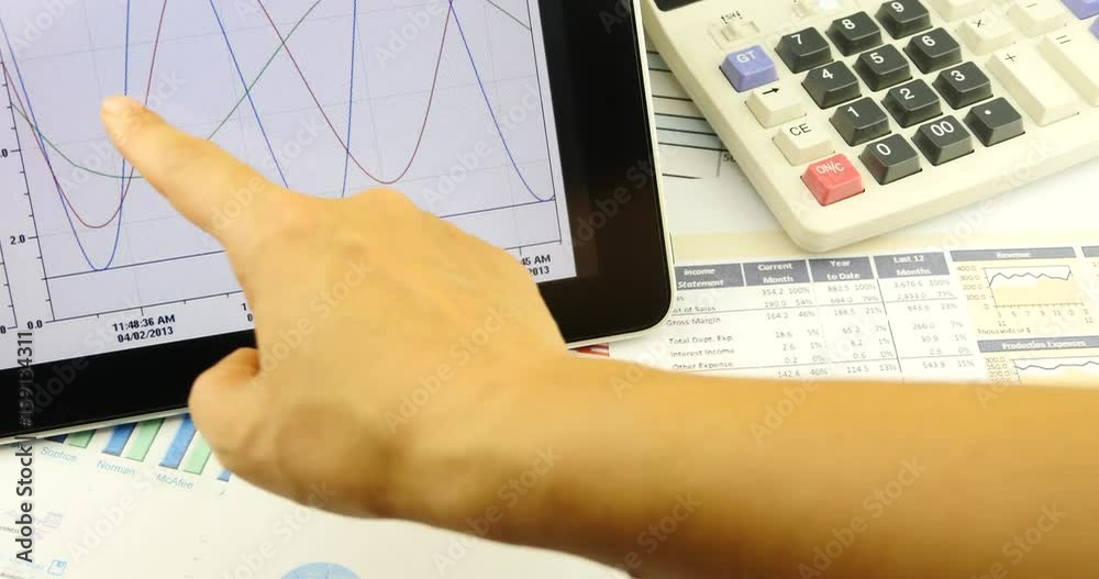 Businessman tapping keyboard operating calculator & working on tablet ...