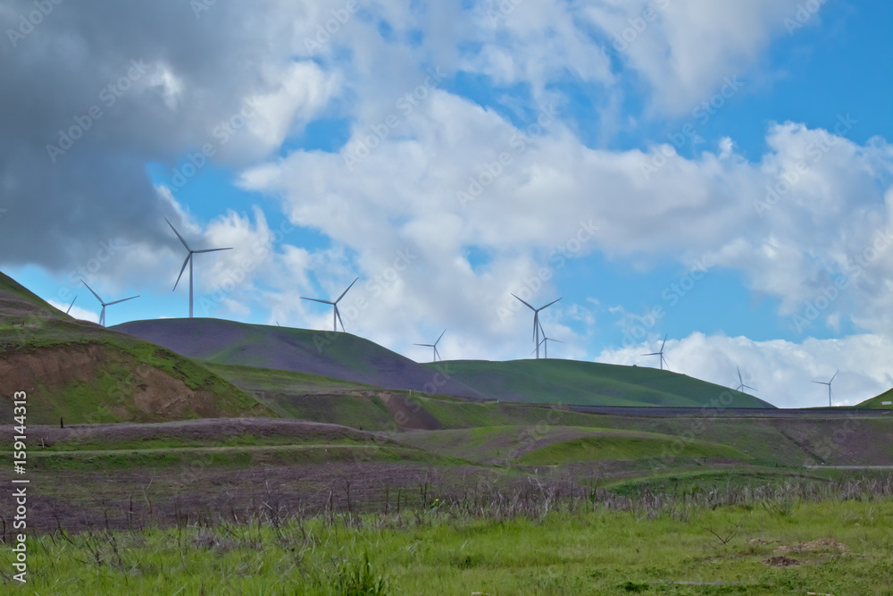 Four wind turbines on a hillside, against the backdrop of cloud-filled ...
