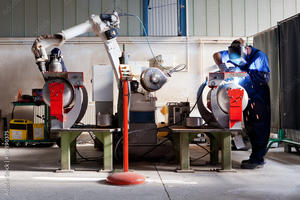 Foto de Man and robotic machine work together inside industrial ...