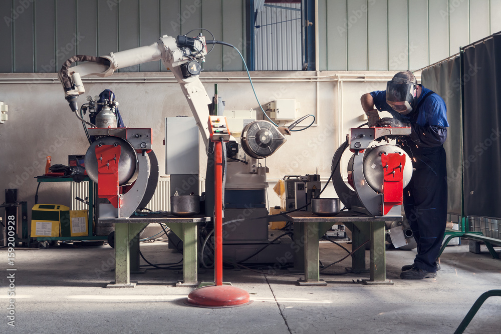 Man and robotic machine work together inside industrial building. The ...