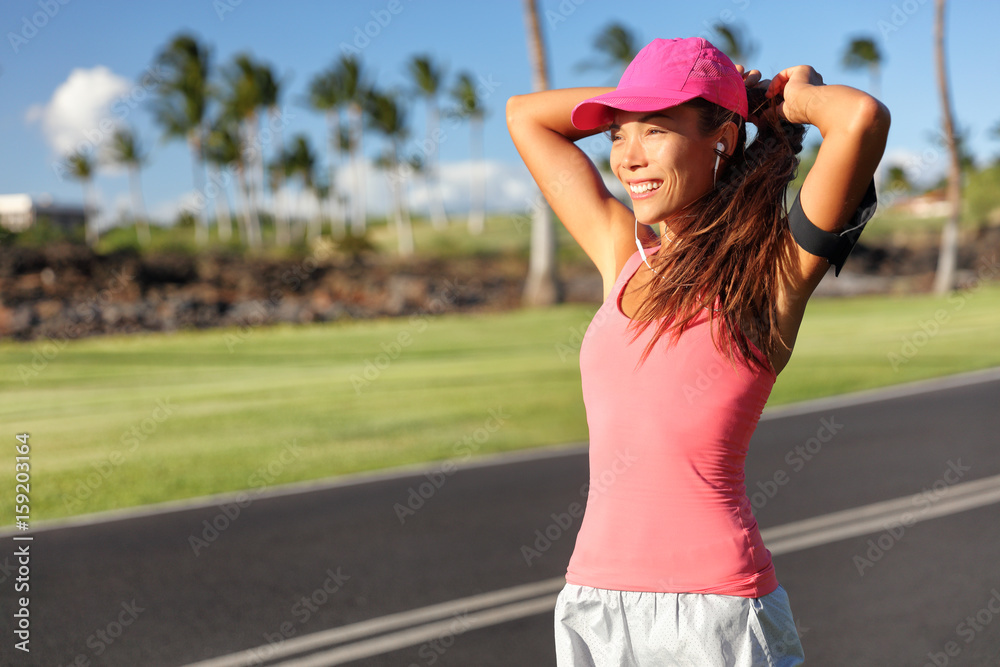 Active Asian runner woman tying hair into ponytail getting ready to run ...
