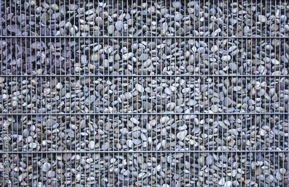 Foto de Steinwand aus Kieselsteinen hinter Gitterzaun do Stock | Adobe ...