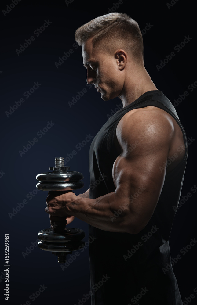 Handsome power athletic man in training pumping up muscles with ...