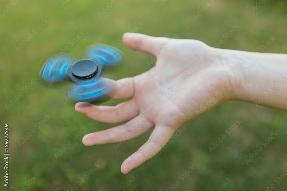Girl's hand holding a spinning fidget spinner in her hand, spinning ...