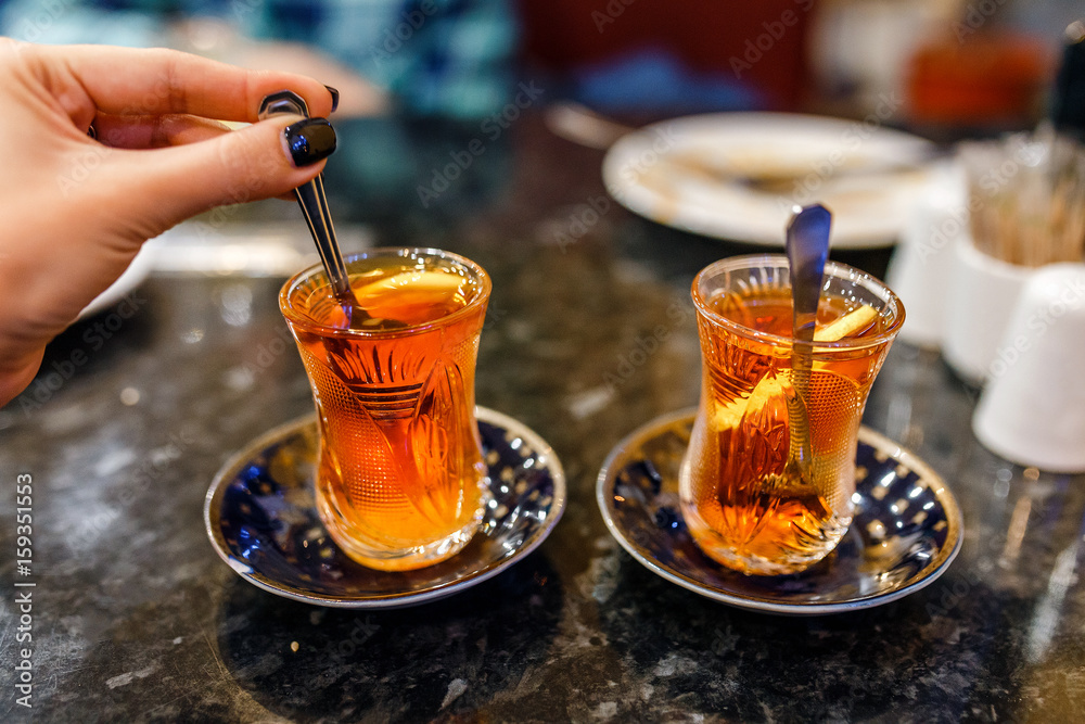Turkish tea with traditional tea glass in cafe, with female hand at ...