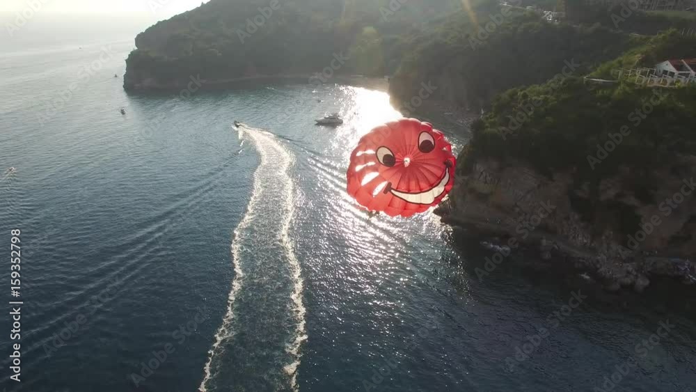Red smile parachute. Paragliding behind a motor boat In Montenegro bay ...