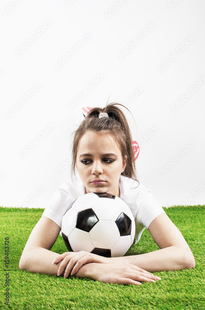 Beautiful girl in a sports T-shirt with a ball on a gray background.Sad ...
