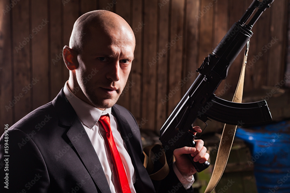 Contract killer holding machine gun in hand Stock Photo | Adobe Stock