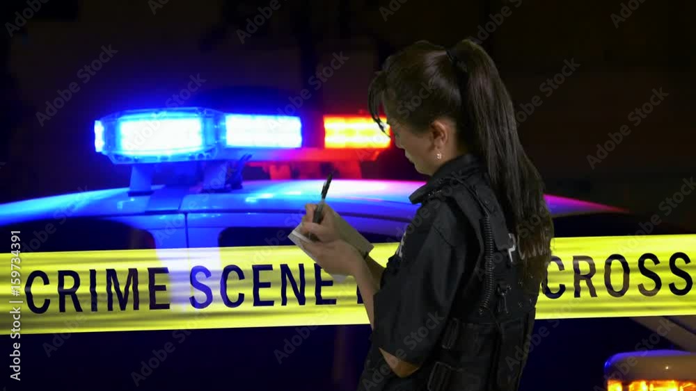 Female Asian American policewoman taking notes at crime scene with ...