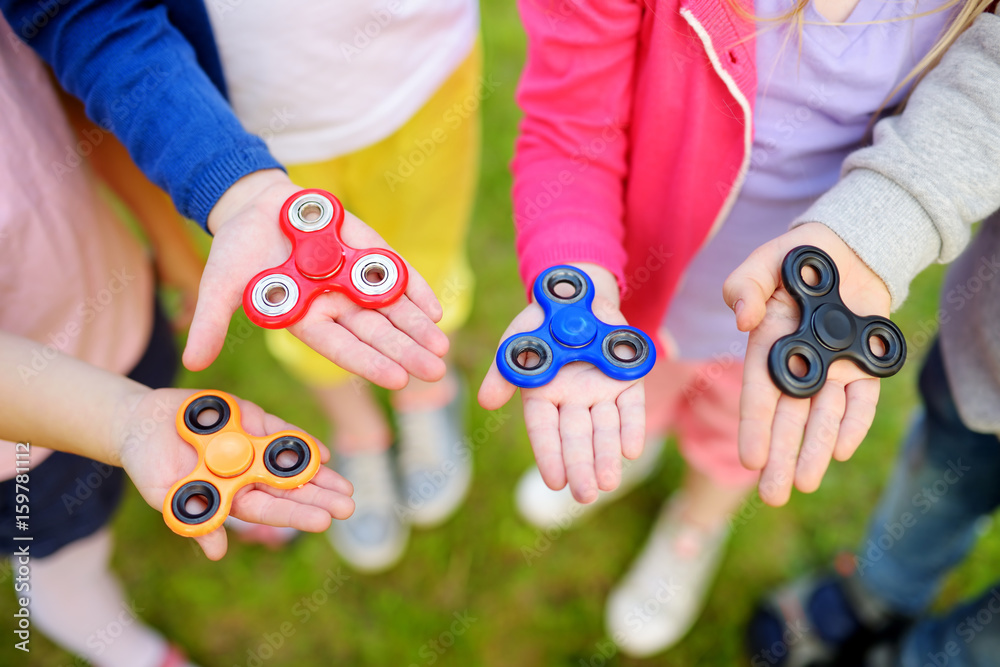 Foto de Four school children playing with fidget spinners on the ...