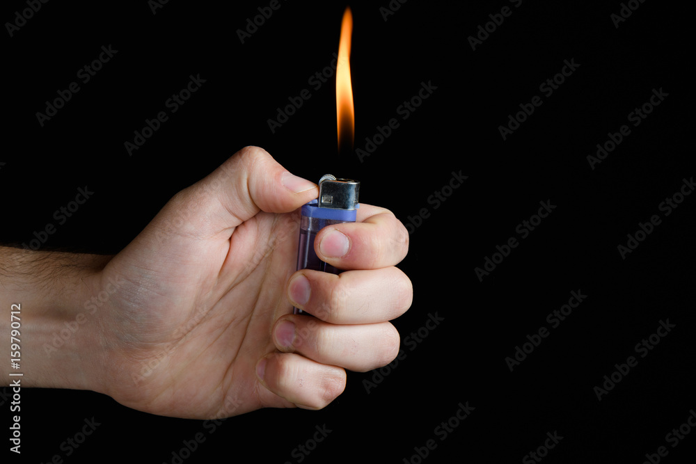 Male hand holding a purple lighter in her fist with a large flame on a ...