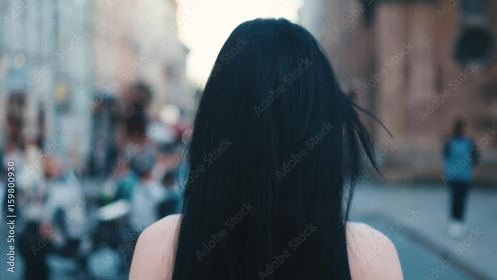 Back view of gorgeous brunette woman walking down the crowded street ...