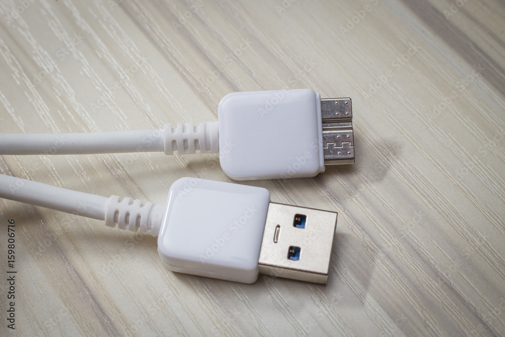 White usb 3.0 cable with micro B connector on wood background close up ...