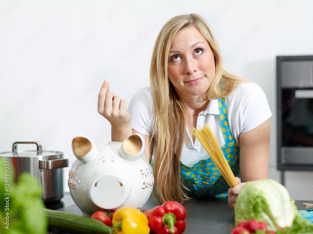 Woman in kitchen saves ready cash with cooking Stock-Foto | Adobe Stock