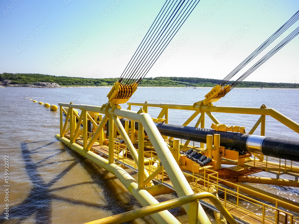 Laying of pipes with pipe-laying barge crane near the shore. Descent of ...