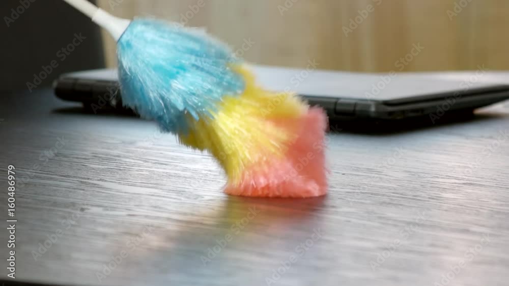 Colorful duster close up. Dust brush wiping wooden table. Office ...