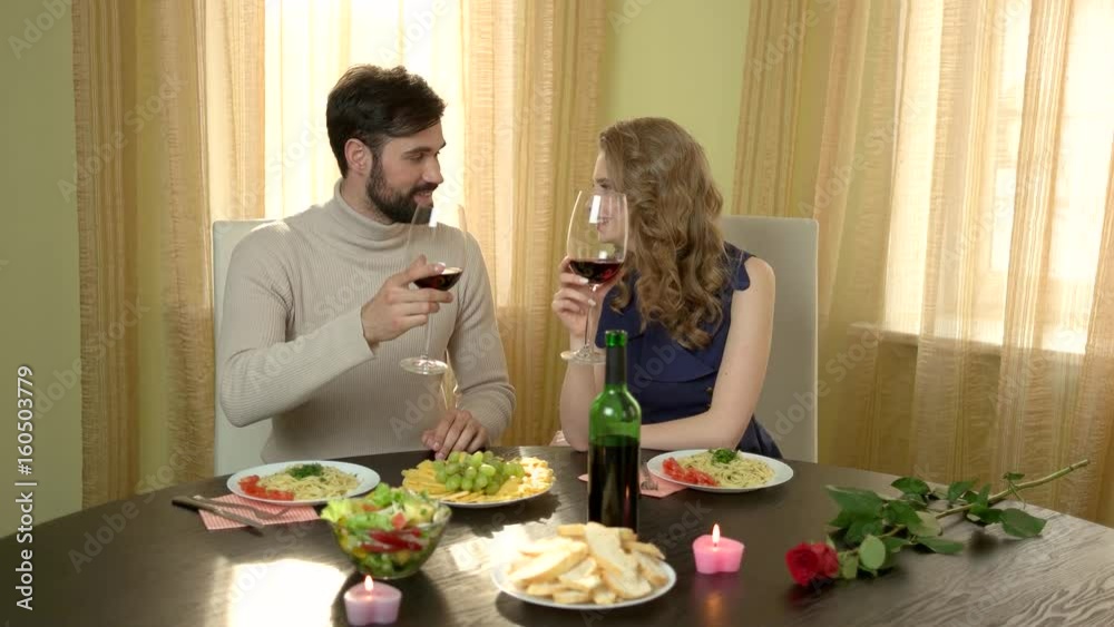 Couple at table drinking wine. Man and woman clinking glasses ...