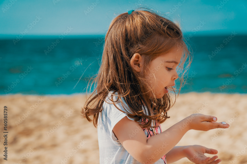 Little cute girl holding a sea shell on the beach in summer Stock Photo ...