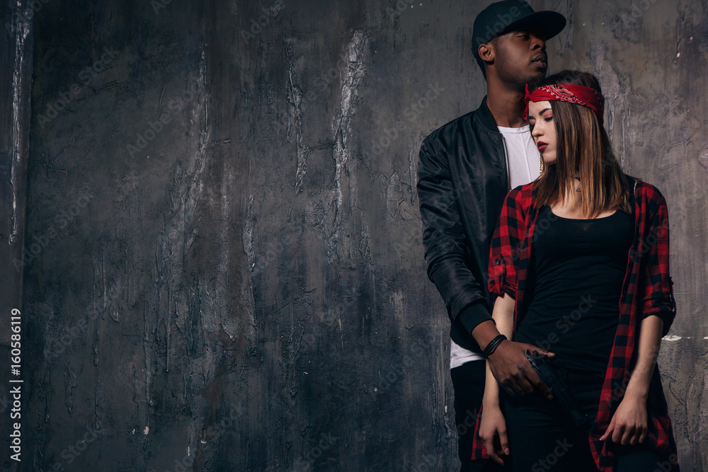 Loving criminal couple with gun. Gang teenagers on dark background ...