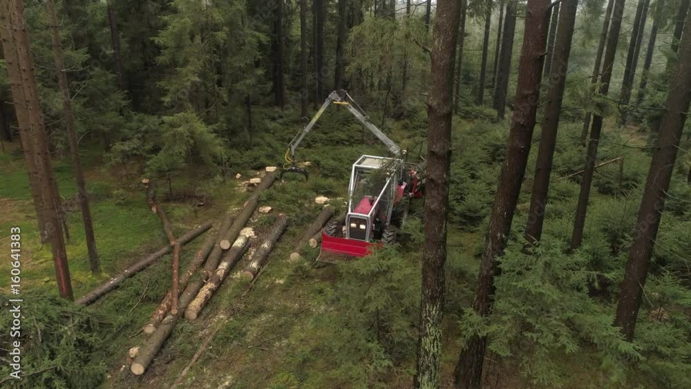 AERIAL, CLOSE UP: Flying above logging truck harvesting, lifting pile ...