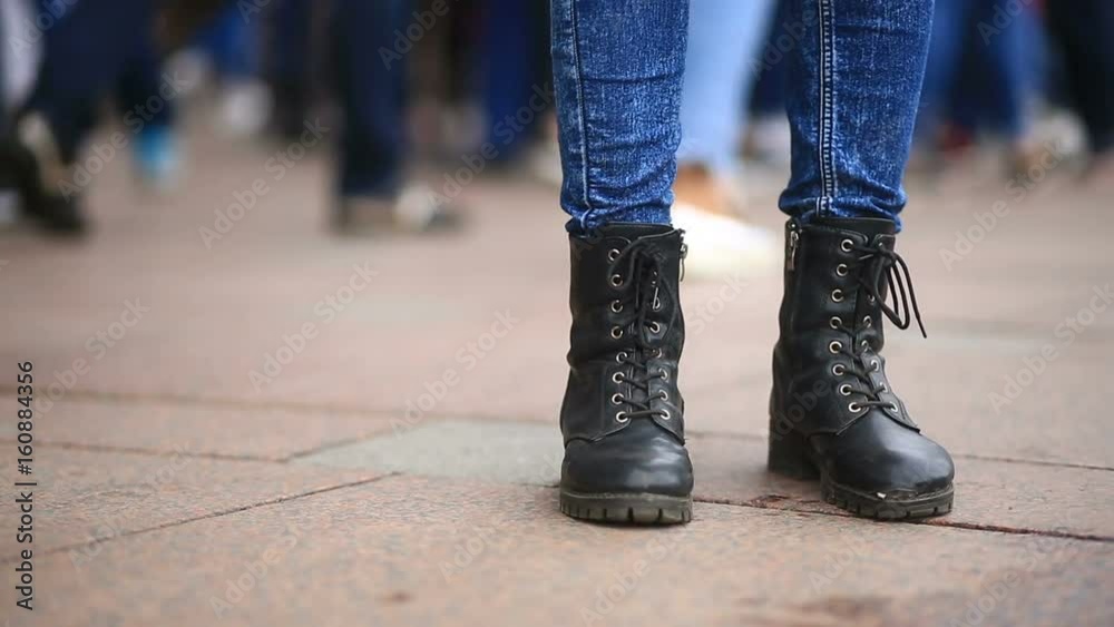 A man in torn, tattered boots on lacing stands in the middle of the ...