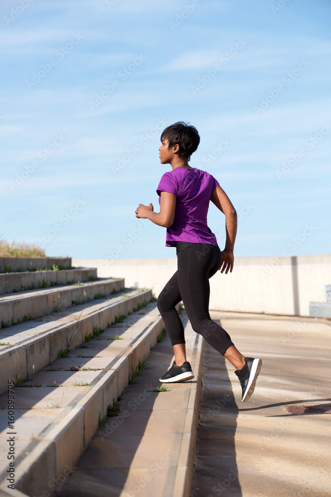 Full length side portrait fit young sports woman running on steps ...