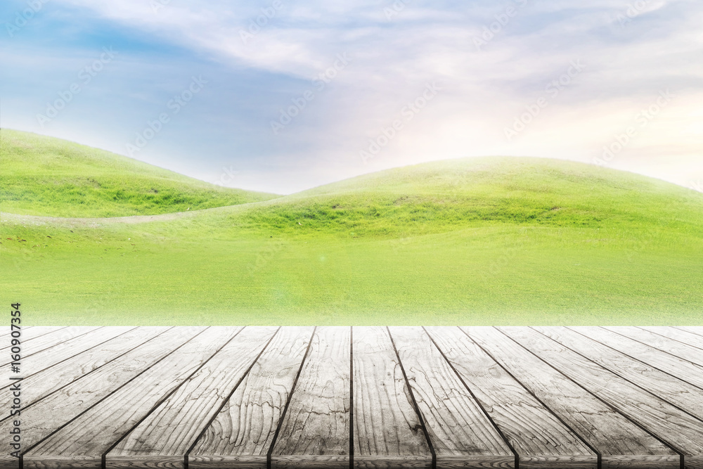 Wood table top on mound slope green grass natural background in morning ...