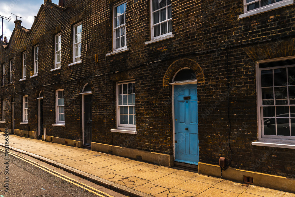 Typical old English buildings, low brick buildings across a narrow ...