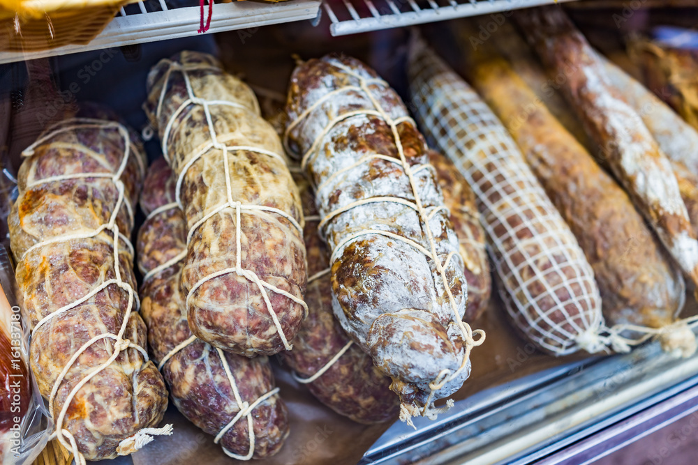 Butcher shop meat closeup with cured salami and ham tied in strings ...