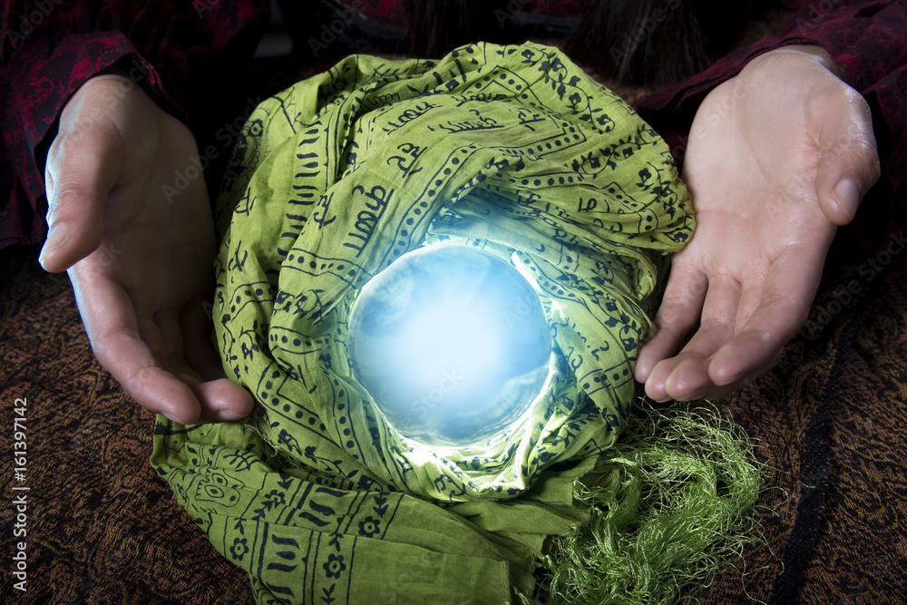 Fortune tellers hands or psychic over a glowing crystal ball. The ...