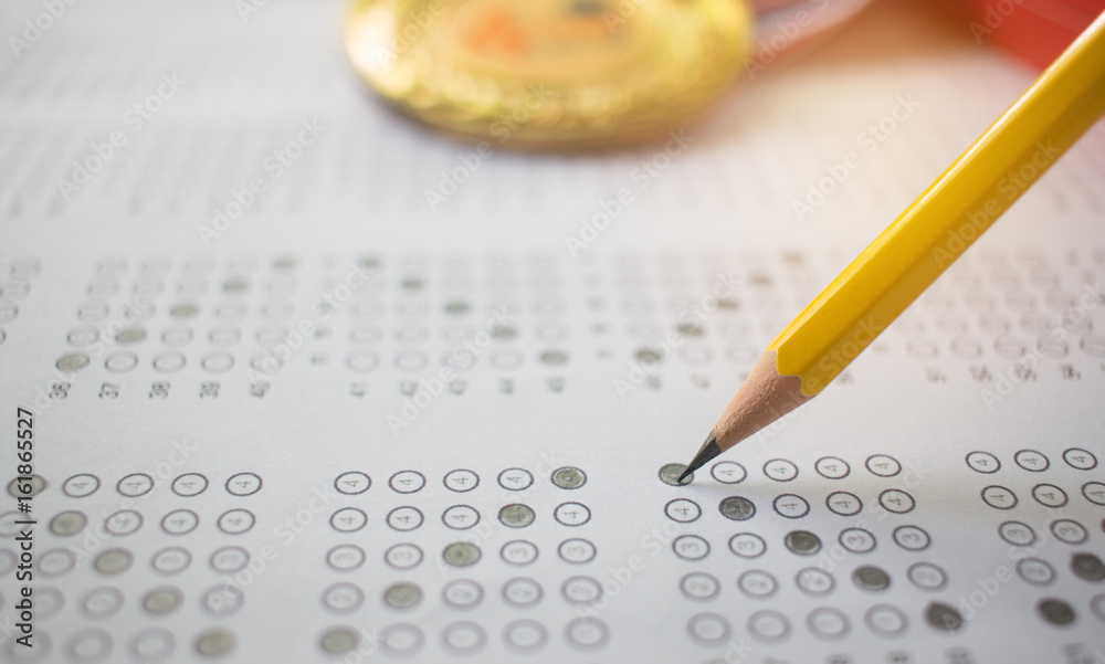 yellow pencil on exam answer sheet with medals blur background ...
