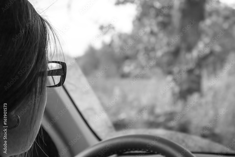 Girl with glasses at the wheel of the car. View from behind the seated ...