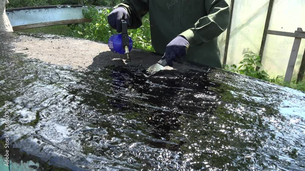 Builder man hands repair lay tar on roof surface with special tools. 4K ...