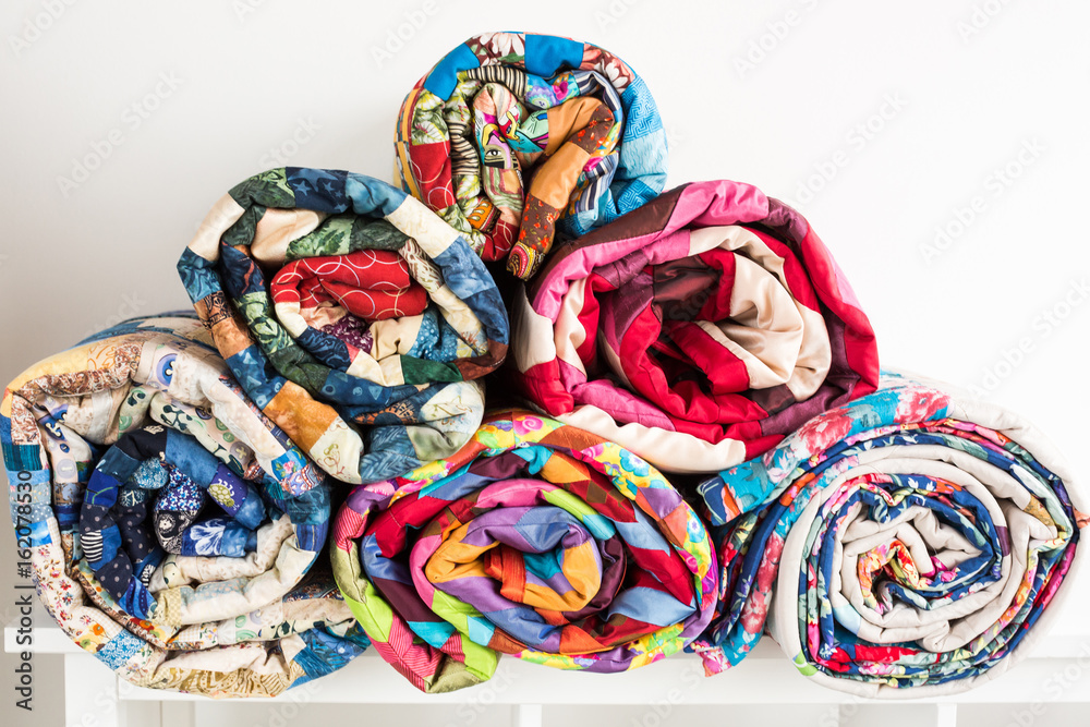 patchwork, sewing and fashion concept - bright beautiful quilts stacked ...