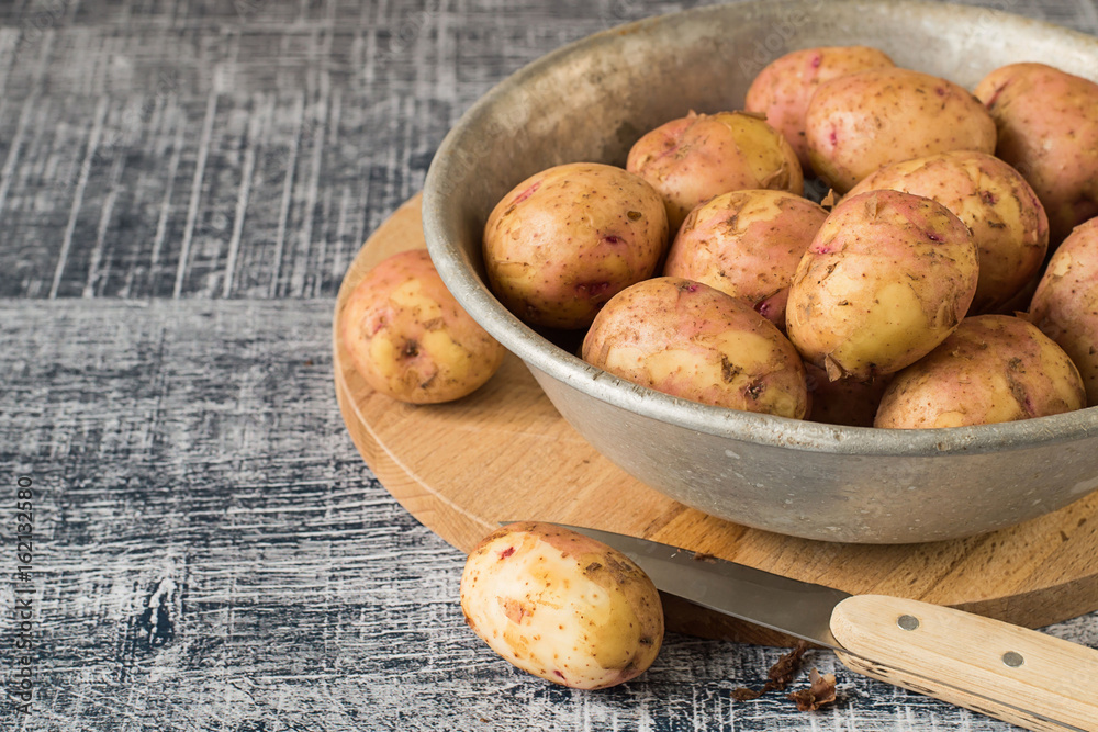 Potatoes. Young early potatoes in an old metal bowl on a wooden ...