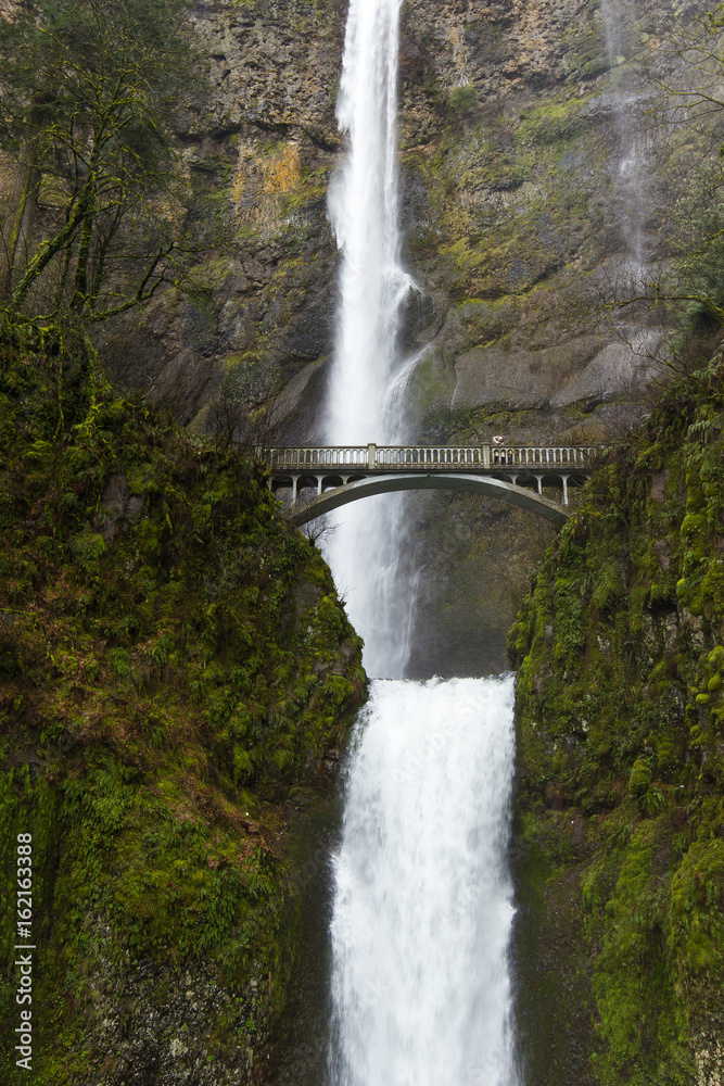 Old bridge over huge and dramatic waterfall during foggy and rainy day ...