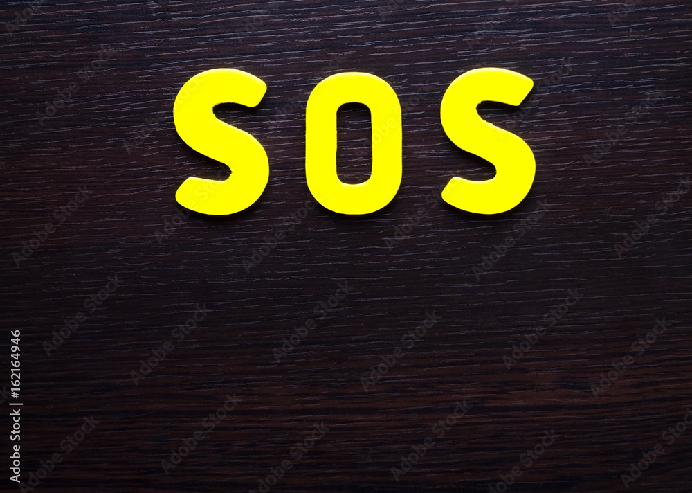 SOS yellow letters on dark brown background. Stock Photo | Adobe Stock