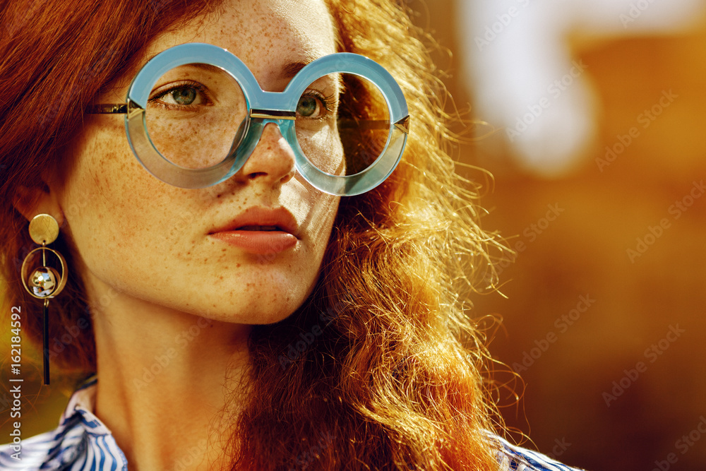 Outdoor close up portrait of young beautiful fashionable redhead girl ...
